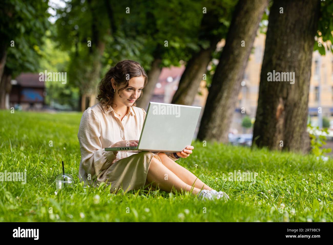 Smiling young woman using laptop typing text answering messages ...