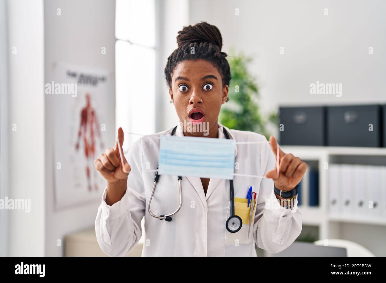 Young african american with braids wearing doctor uniform holding ...