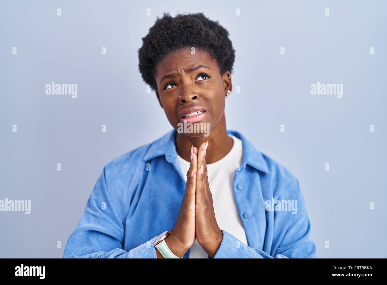 African american woman standing over blue background begging and ...