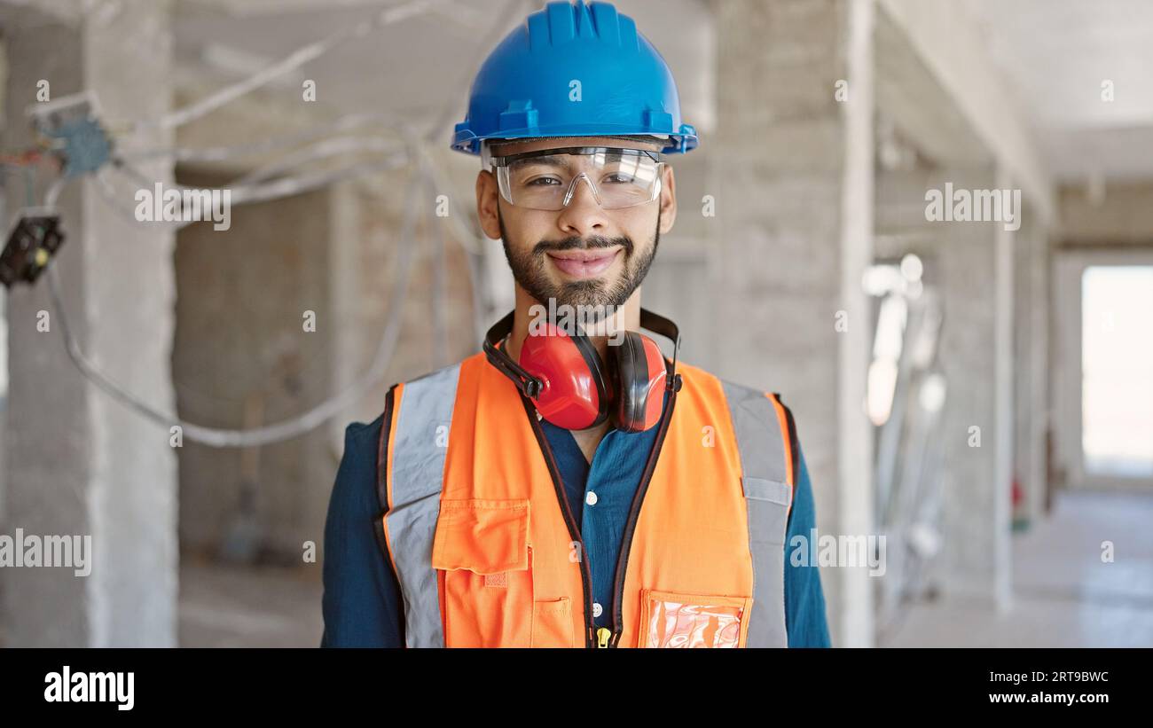 Young hispanic man builder smiling confident wearing hardhat at ...