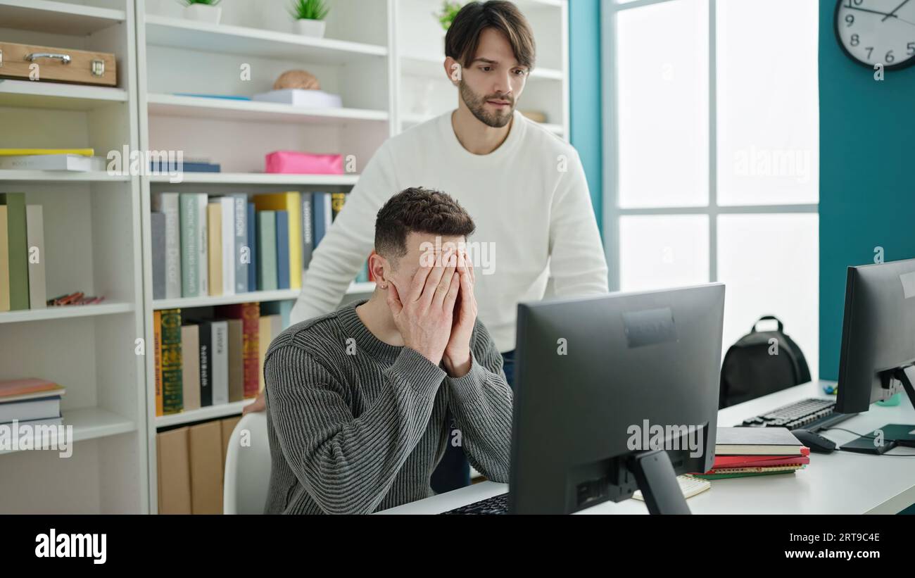 Two men students stressed using computer studying at library university ...