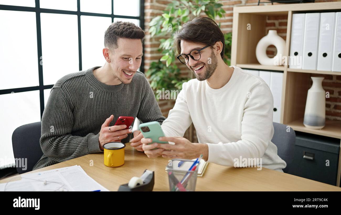 Two men business partners drinking coffee using smartphones at office ...