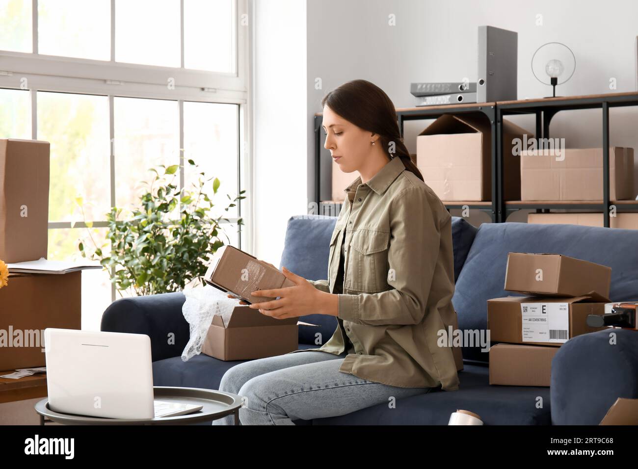 Young woman packing parcel for client at home Stock Photo - Alamy