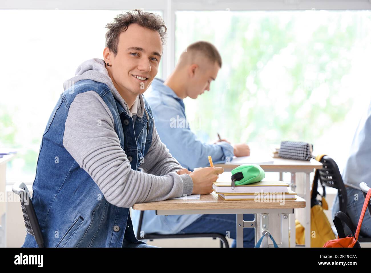 Happy male student sitting with his classmates in classroom Stock Photo ...