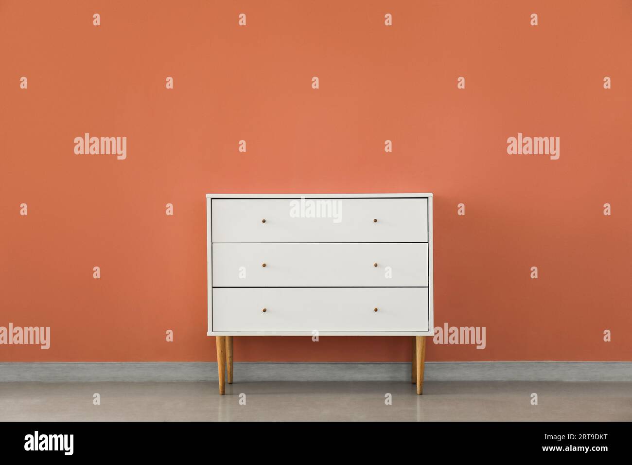 Stylish chest of drawers against color wall Stock Photo - Alamy