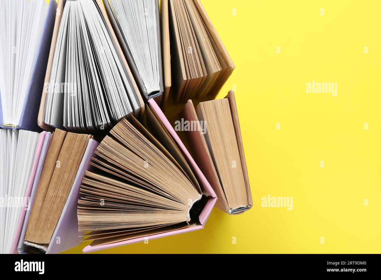 Many half open books on yellow background Stock Photo - Alamy
