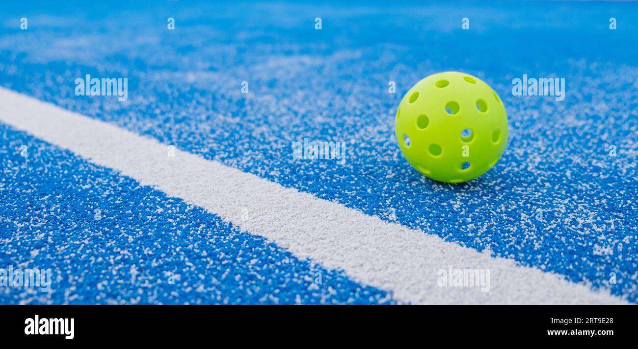 pickleball ball close to the line of a blue pickleball court, banner ...