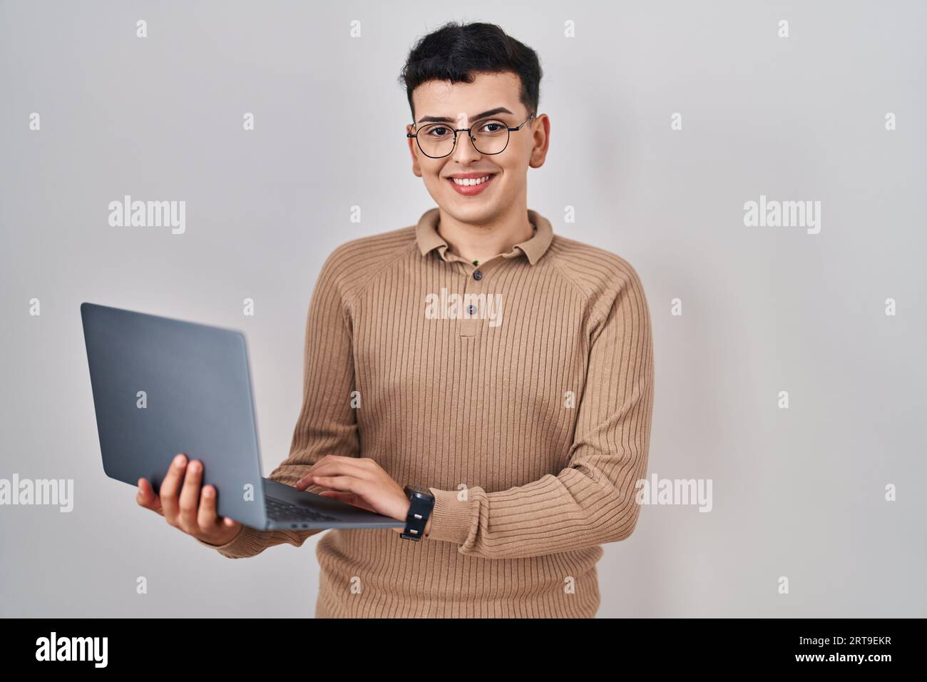 Non binary person using computer laptop with a happy and cool smile on ...
