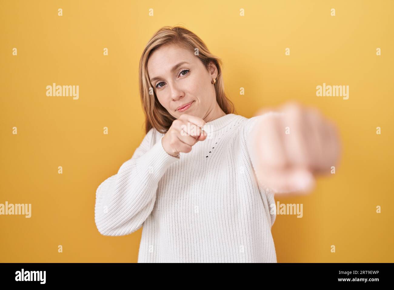 Young caucasian woman wearing white sweater over yellow background ...
