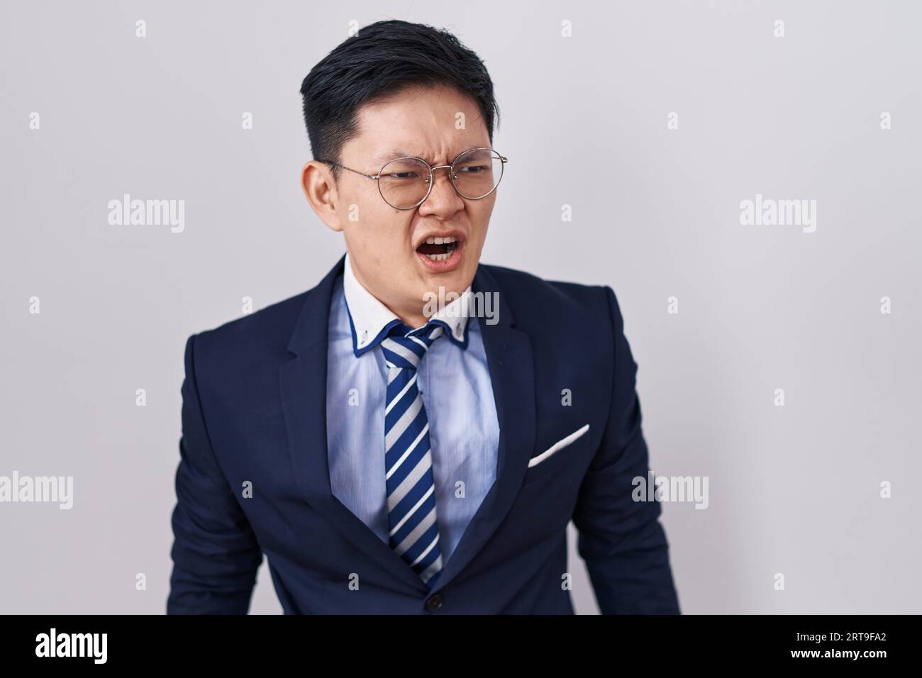 Young asian man wearing business suit and tie angry and mad screaming ...