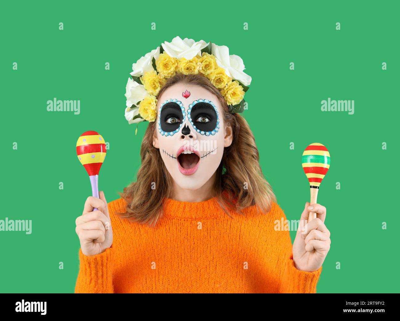 Shocked young woman with painted skull and maracas on green background ...