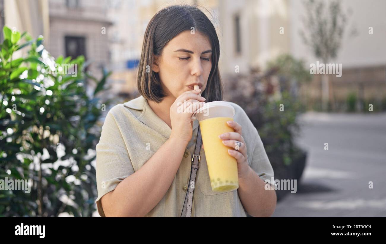 Young beautiful hispanic woman drinking bubble tea in the streets of ...