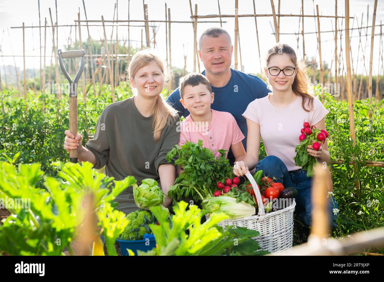 Happy family standing with crop of vegetables in garden Stock Photo - Alamy
