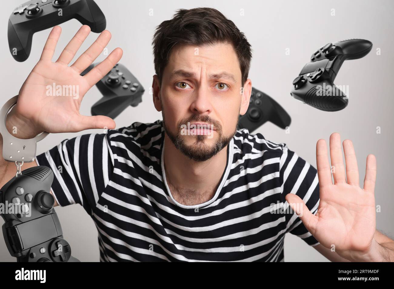 Gaming disorder. Man handcuffed with gamepad stuck to transparent ...