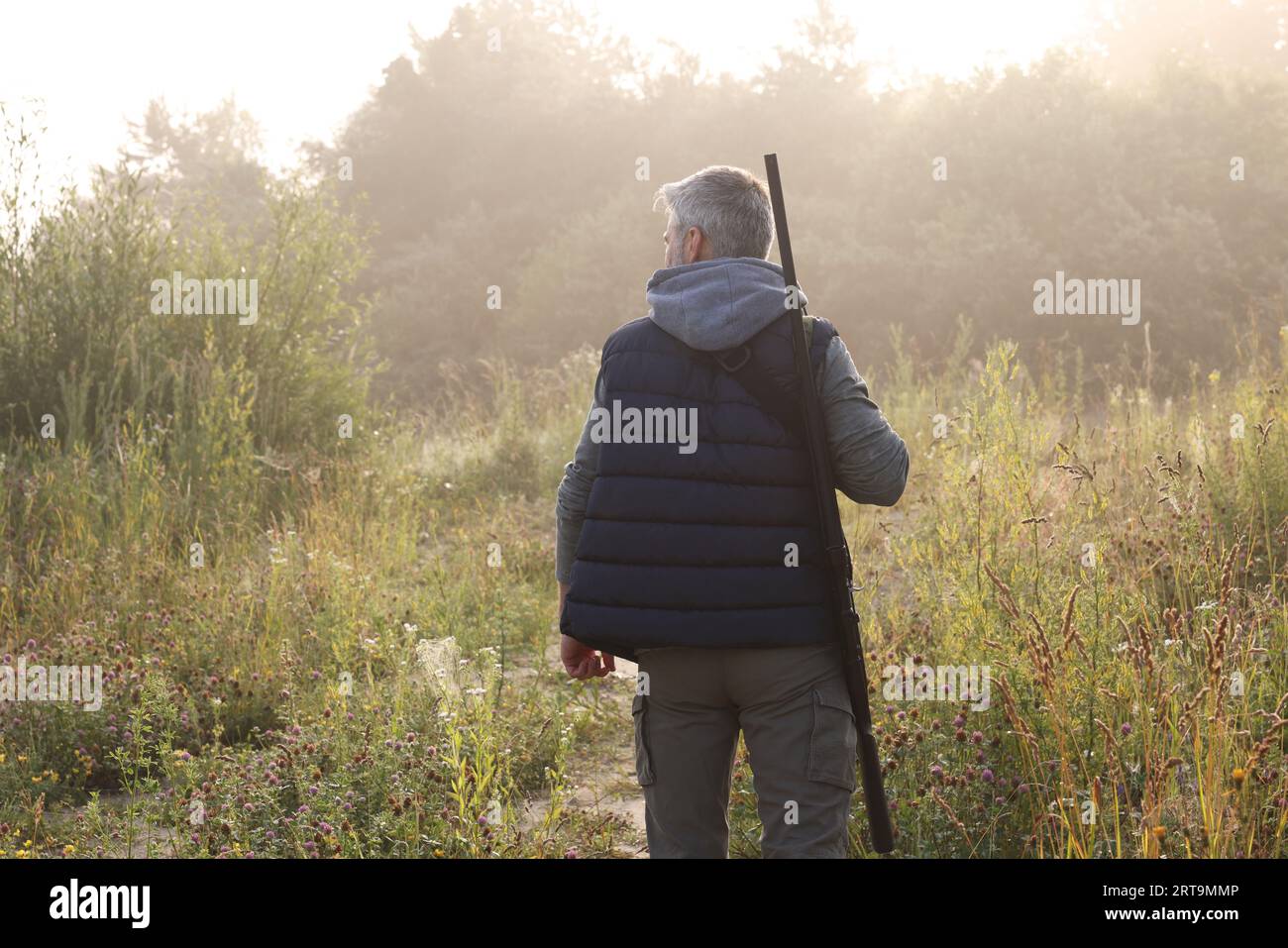 Man with hunting rifle outdoors, back view Stock Photo - Alamy