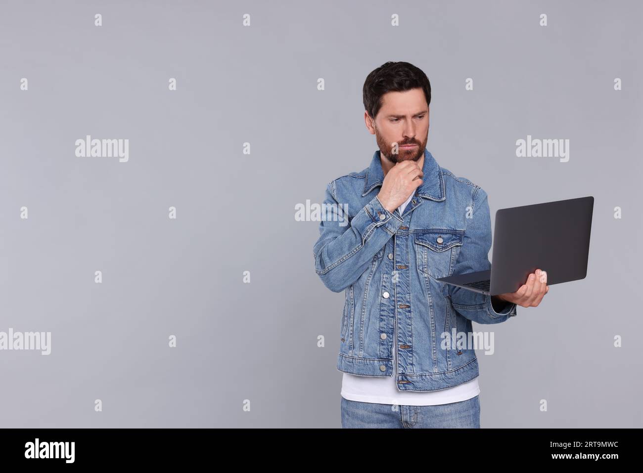Confused man with laptop on light grey background. Space for text Stock ...
