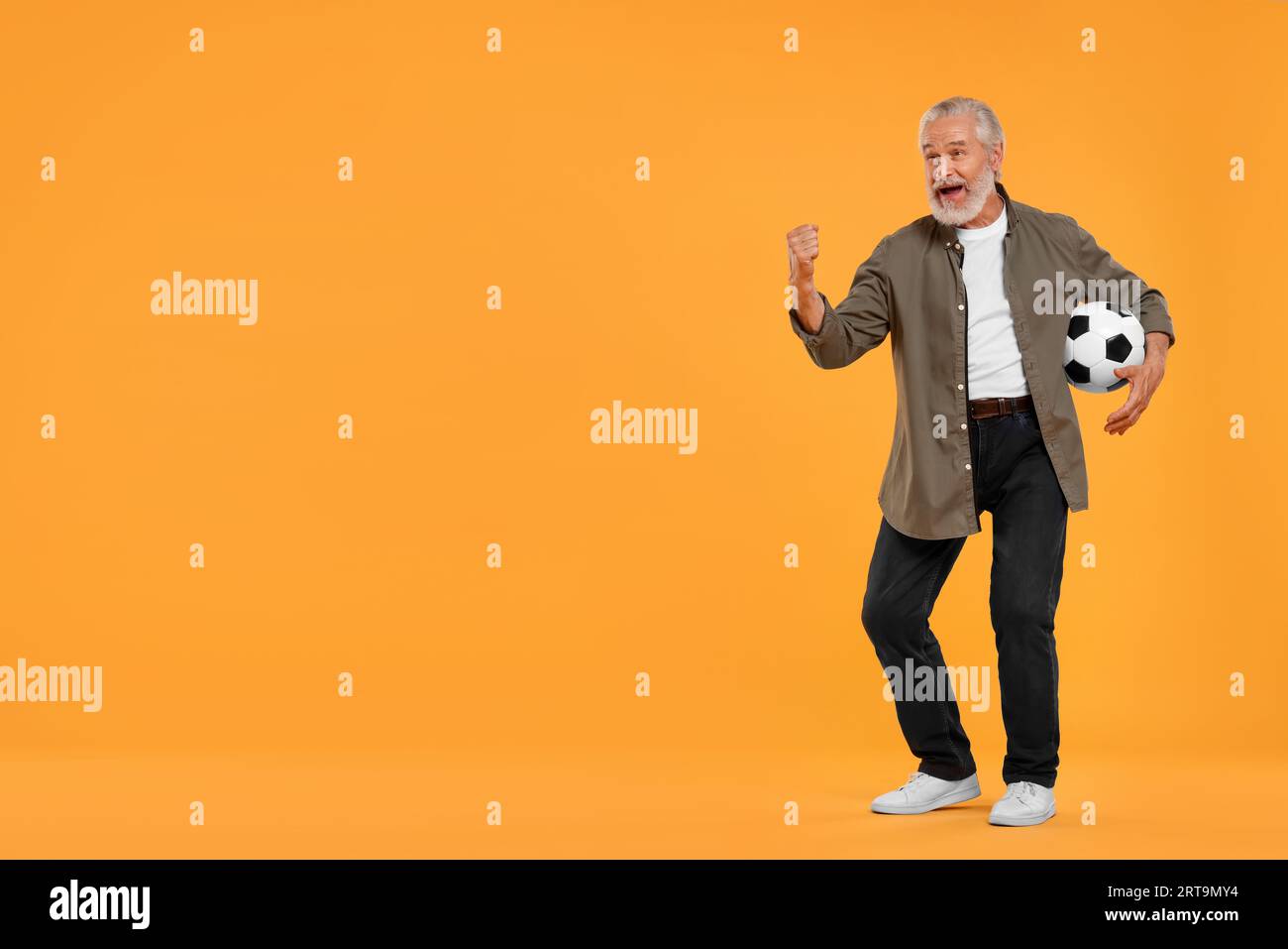 Emotional senior sports fan with soccer ball on yellow background ...