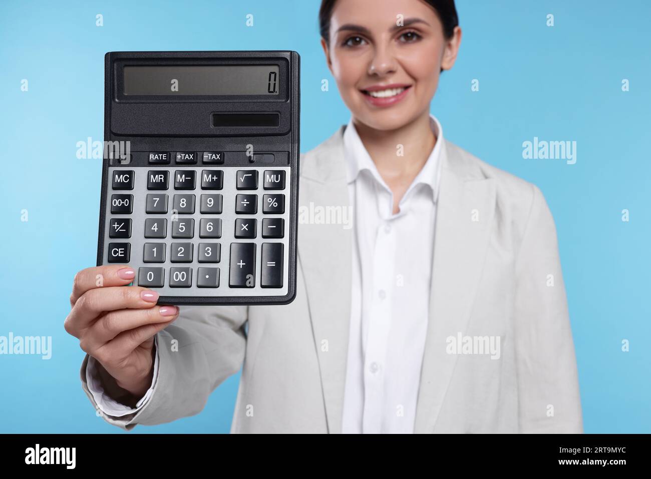 Smiling accountant against light blue background, focus on calculator ...