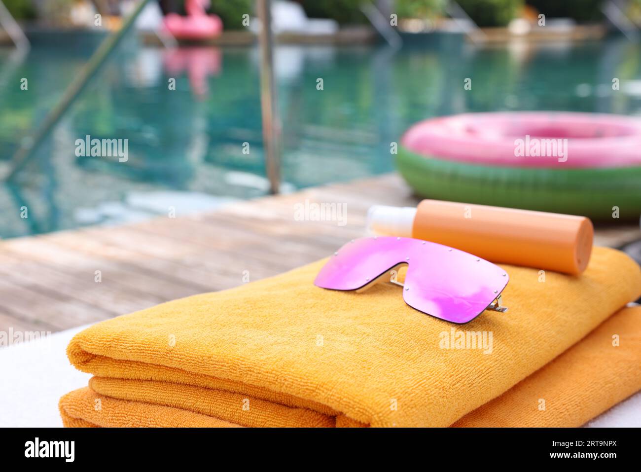 Beach towels, sunglasses and sunscreen on sun lounger near outdoor ...