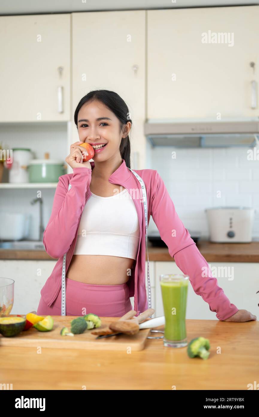 A portrait of a beautiful and healthy Asian woman in sportswear stands ...