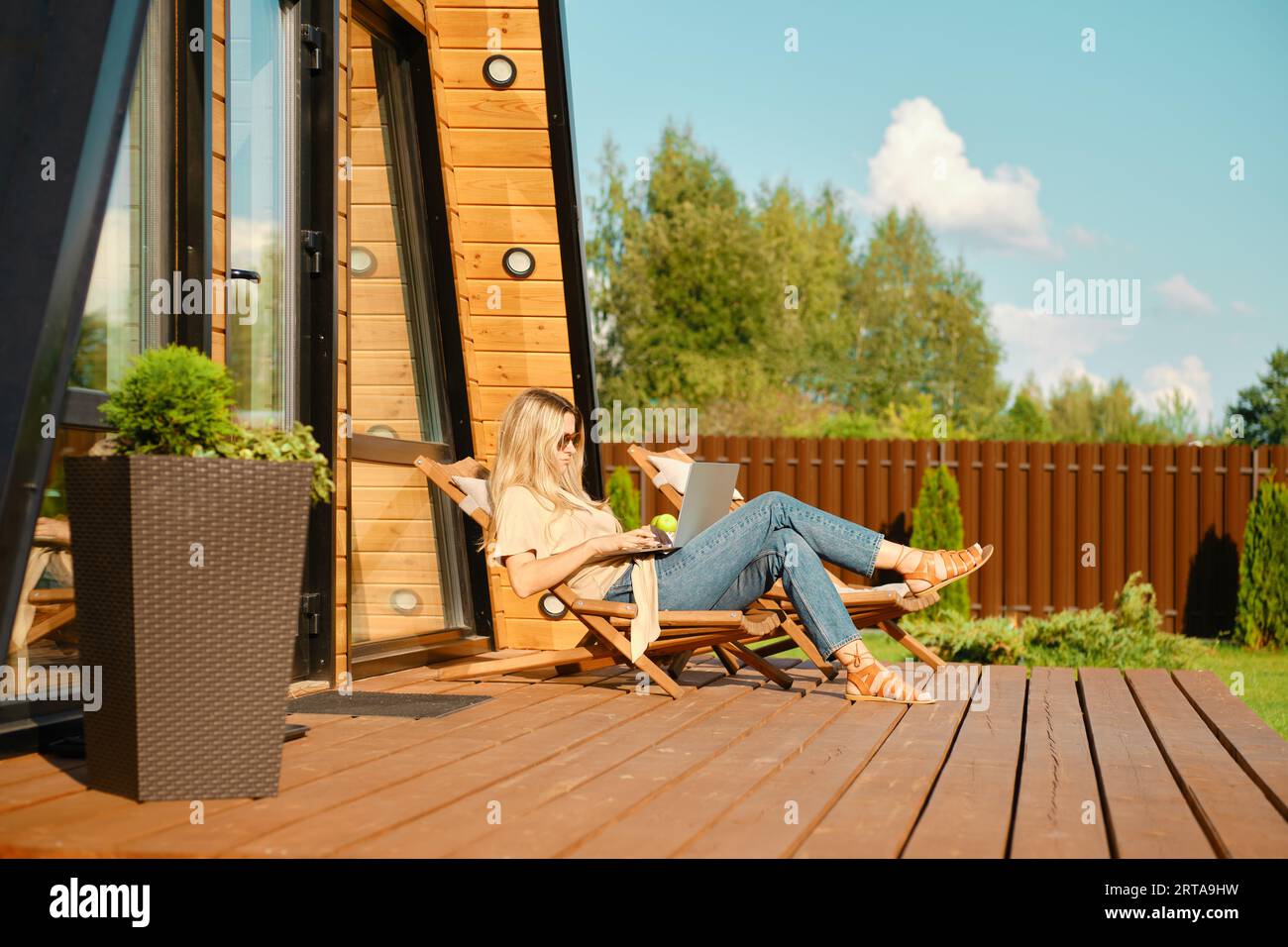 Woman watching movie on laptop while resting in a folding wooden sun ...