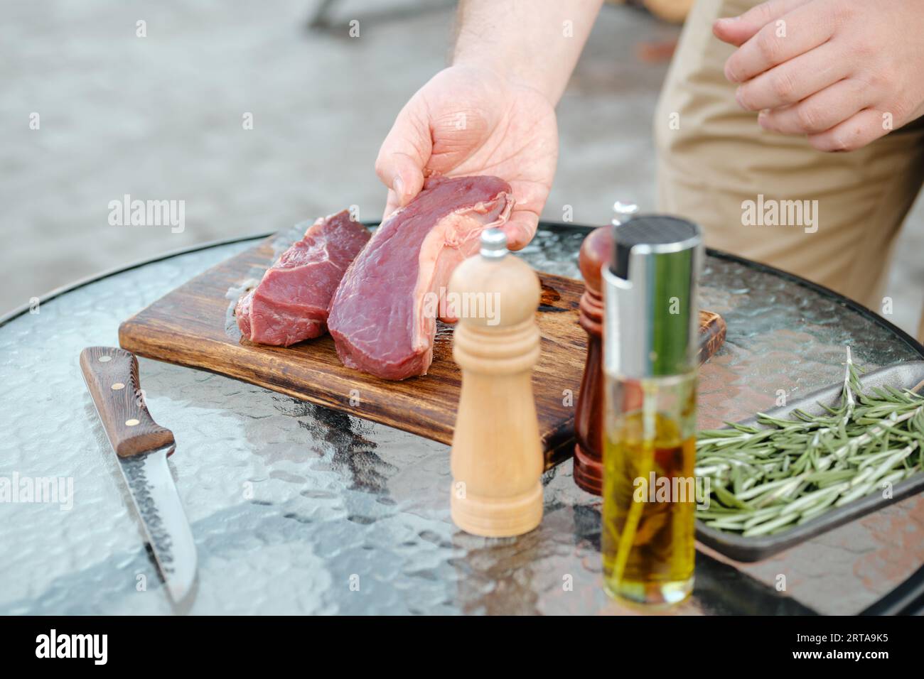 Unrecognizable man turning on other side raw beef strip steak to season ...