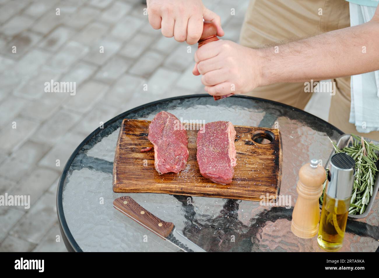 Top view of unrecognizable man seasoning raw beef steak with pepper ...