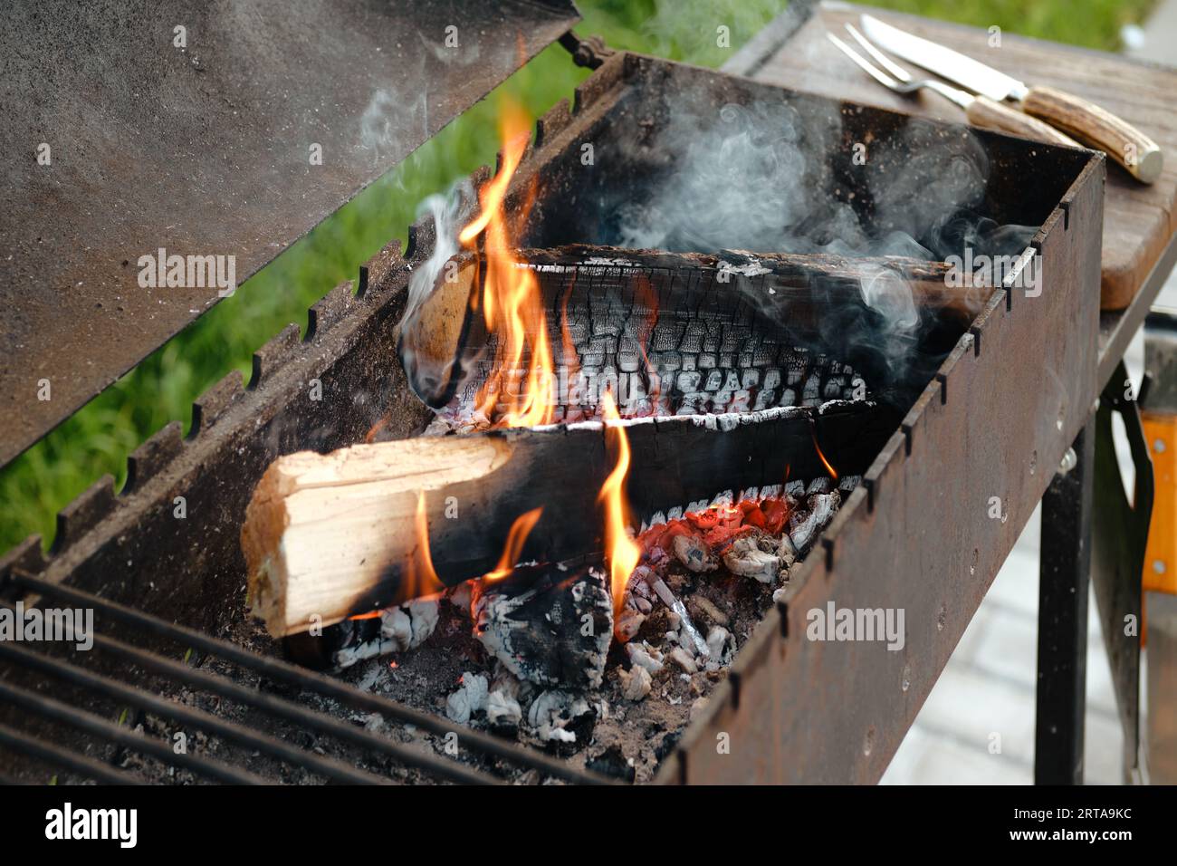 Metal grill with burning log and fork and knife for steak Stock Photo ...