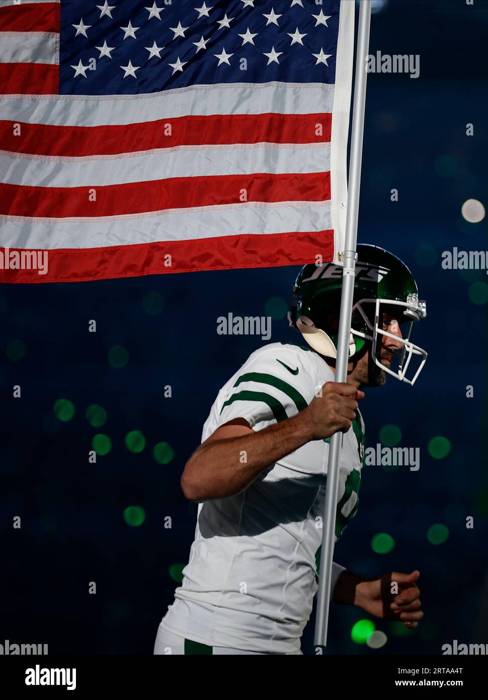 New York Jets quarterback Aaron Rodgers (8) carries an American flag ...