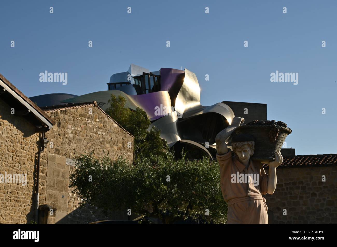 An ornate sculpture is situated in front of a modern building and a ...