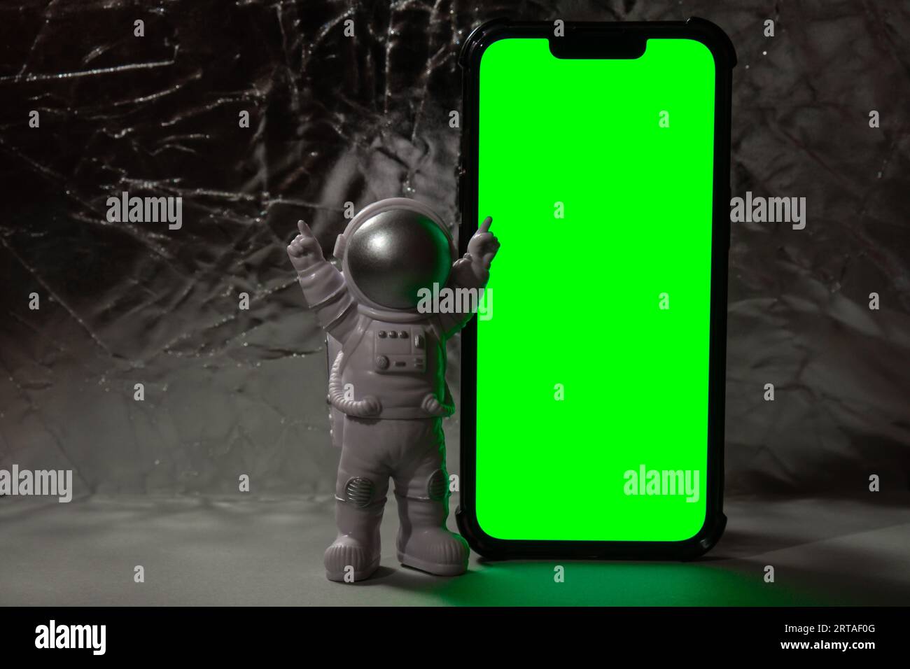 Plastic toy figure astronaut with mobile phone chroma key green screen ...