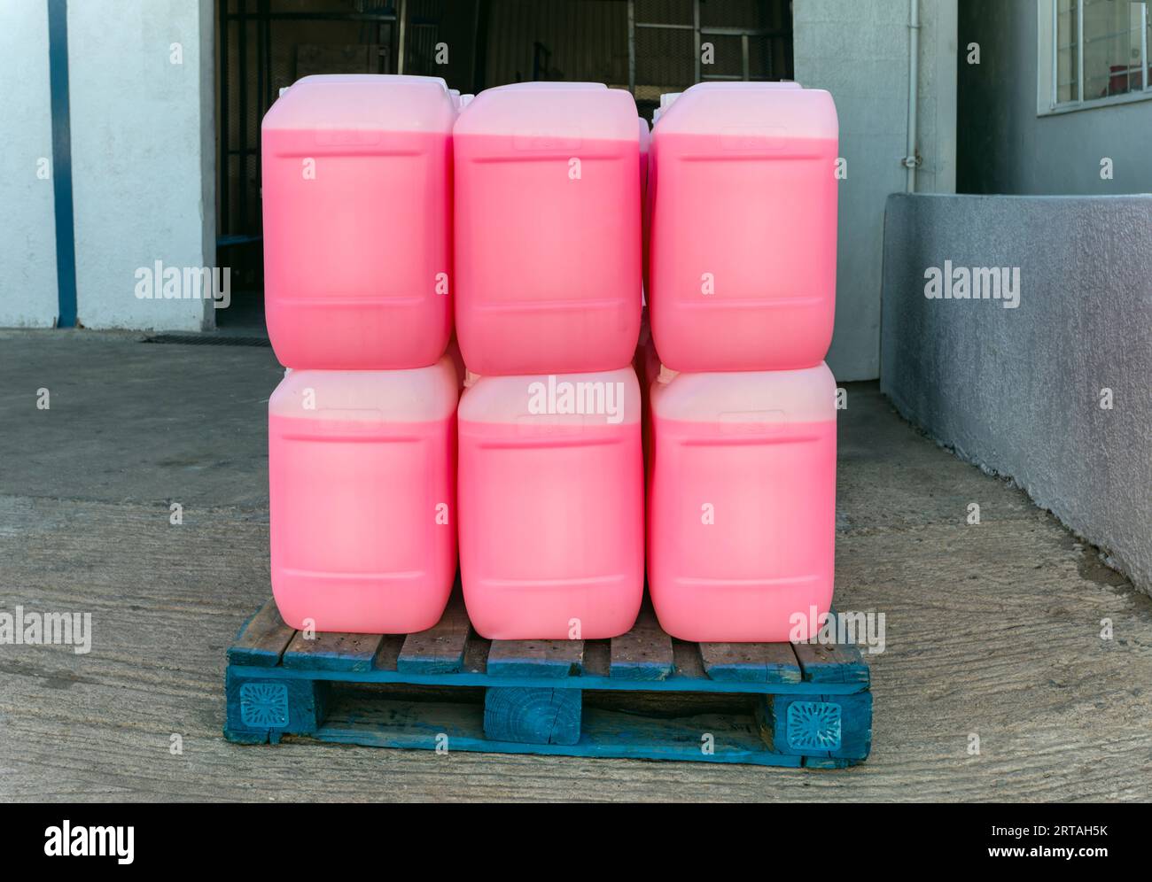 stacked plastic containers with a pink liquid on a wooden pallet ready ...