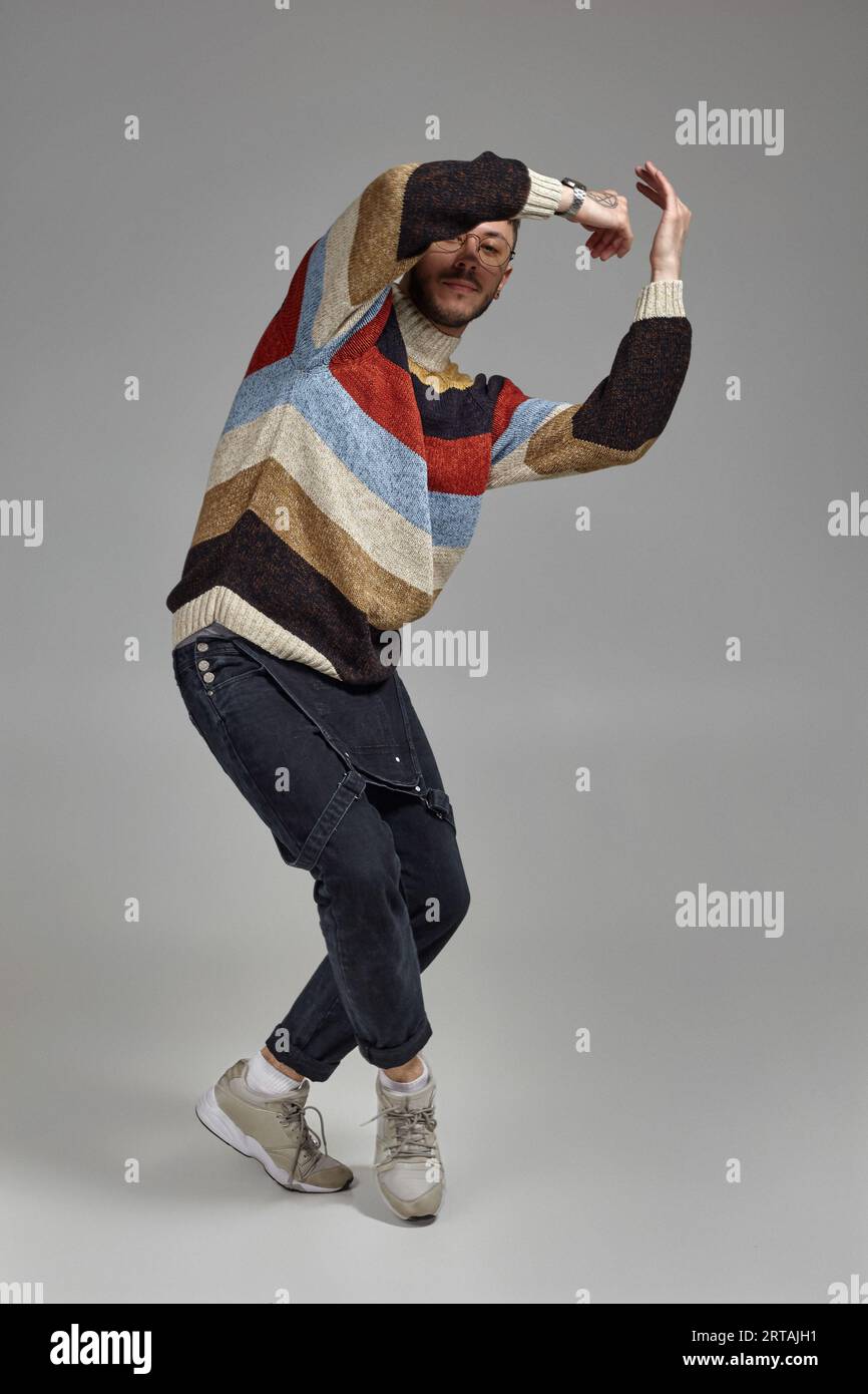 Full-length portrait of a funny guy dancing in studio on a gray ...