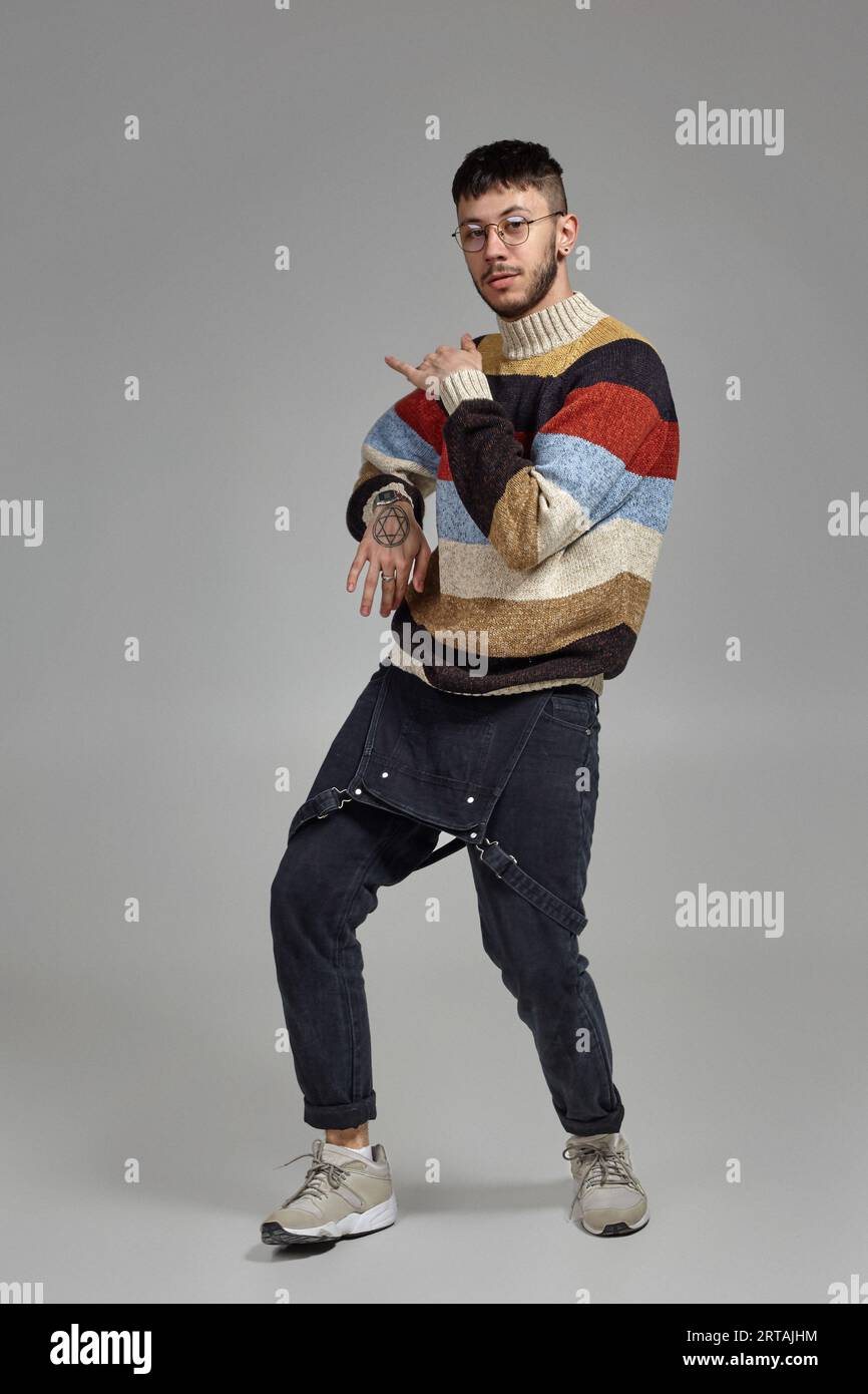 Full-length portrait of a funny guy dancing in studio on a gray ...