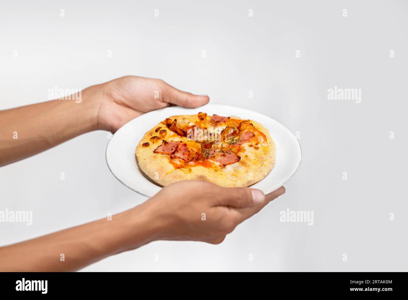 A human hand holding pizza on a plate with a white background Stock ...
