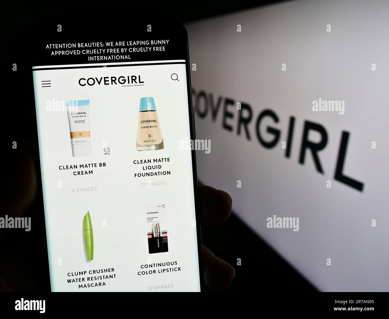 Person holding mobile phone with web page of US cosmetics company ...