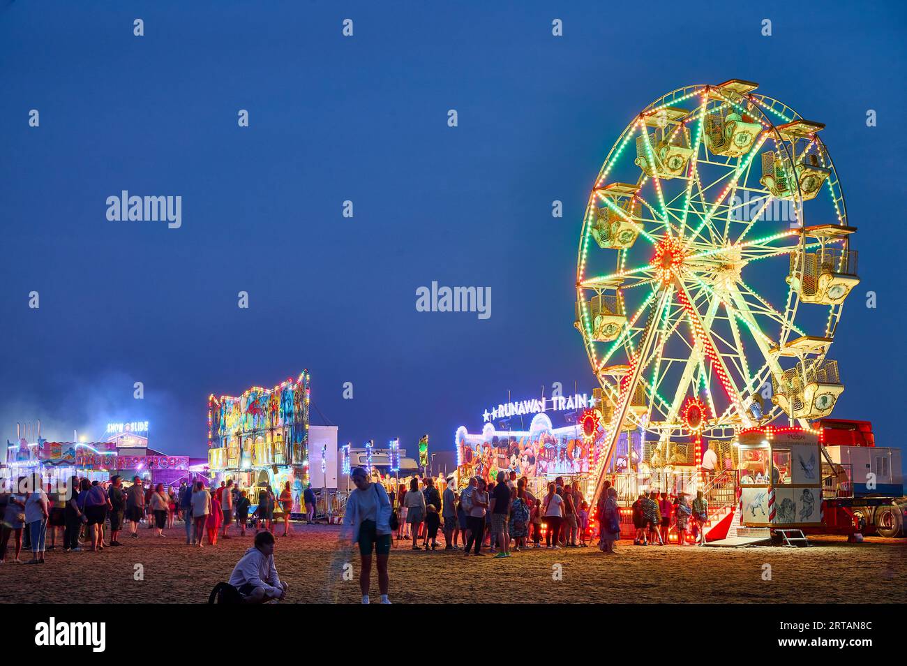 Funfair at night on beach in summer. Runaway Train and Ferris wheel ...