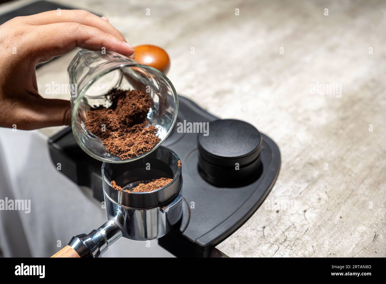 Barista hand pouring fresh ground coffee into the portafilter. Make ...