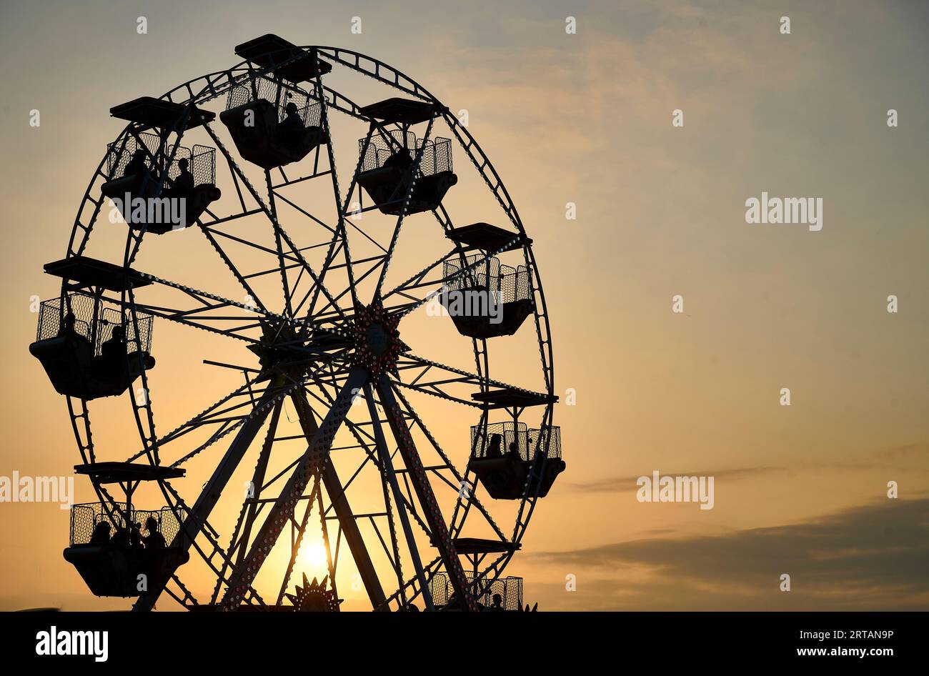 Sun setting behind fairground Ferris wheel Stock Photo - Alamy