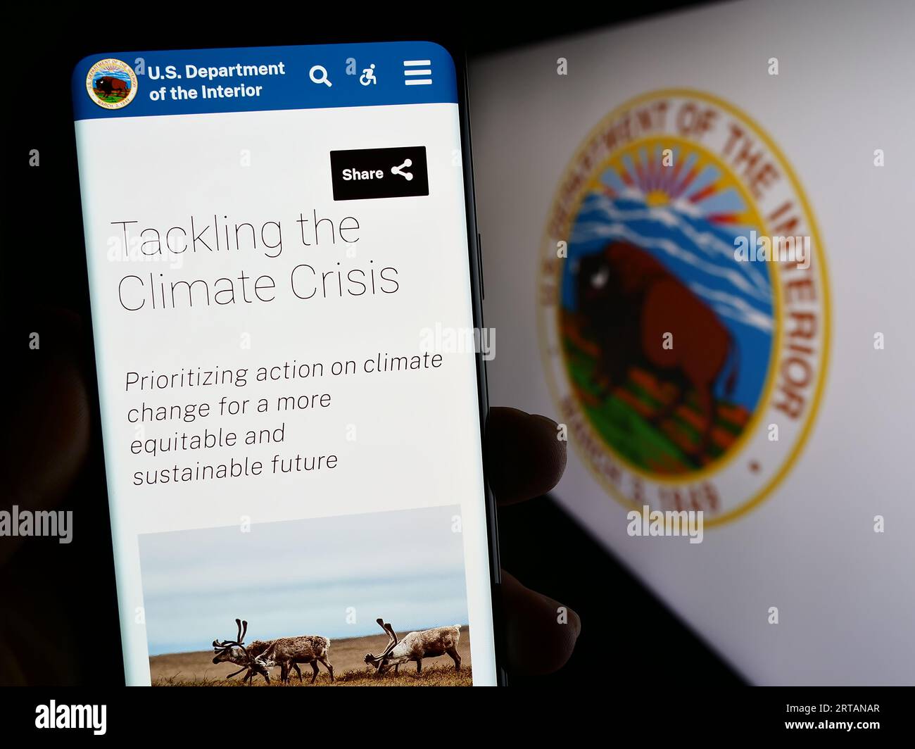 Person holding mobile phone with web page of U.S. Department of the ...