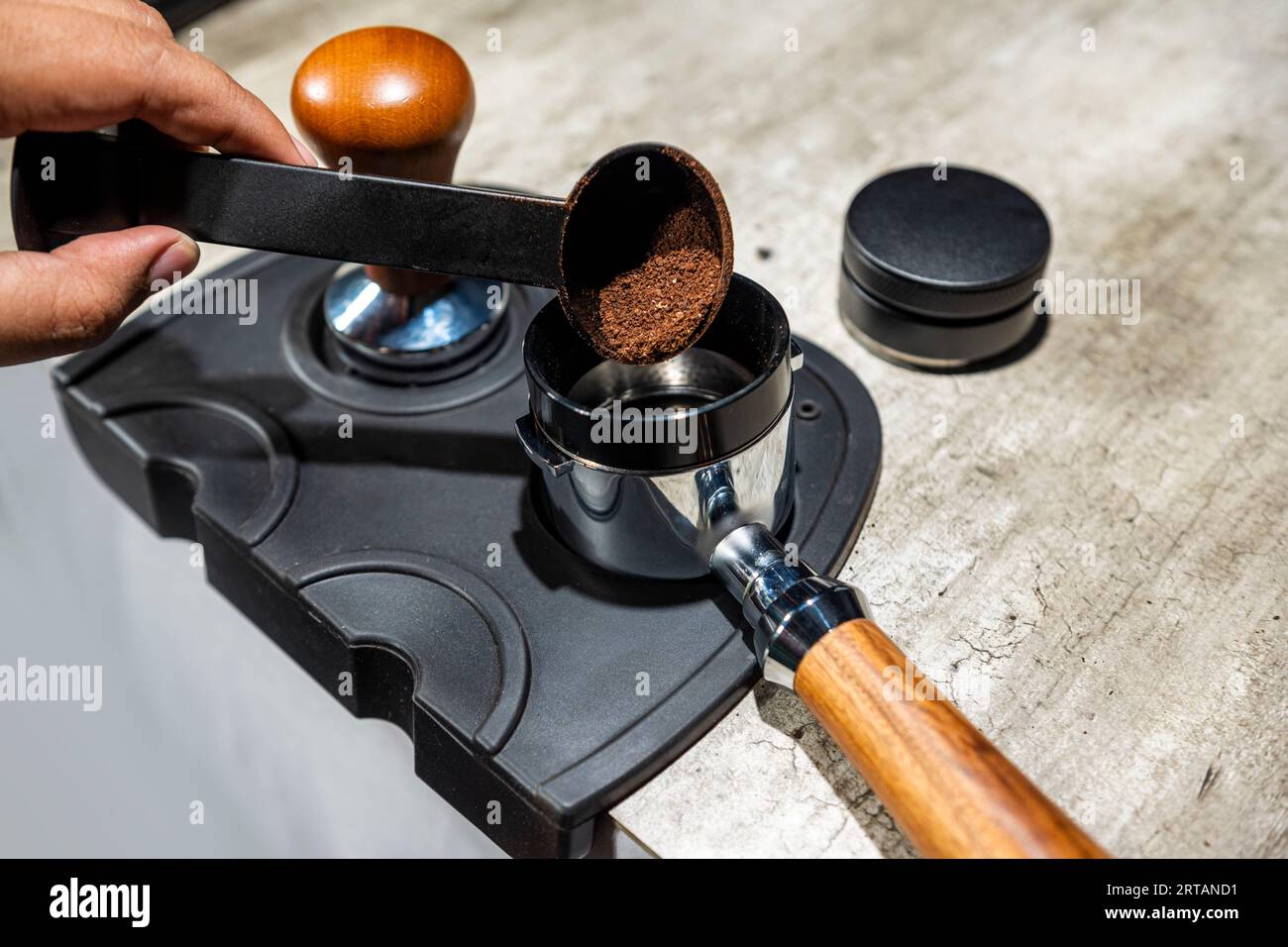 Barista hand pouring fresh ground coffee into the portafilter. Make ...