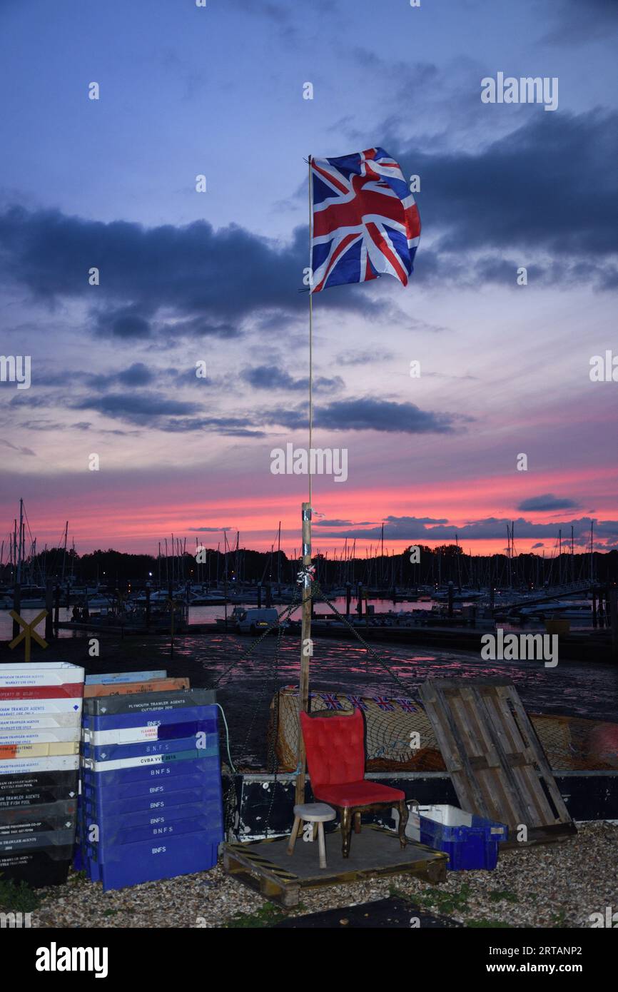 Union flag flying above a red chair in the sunset on the banks of the ...