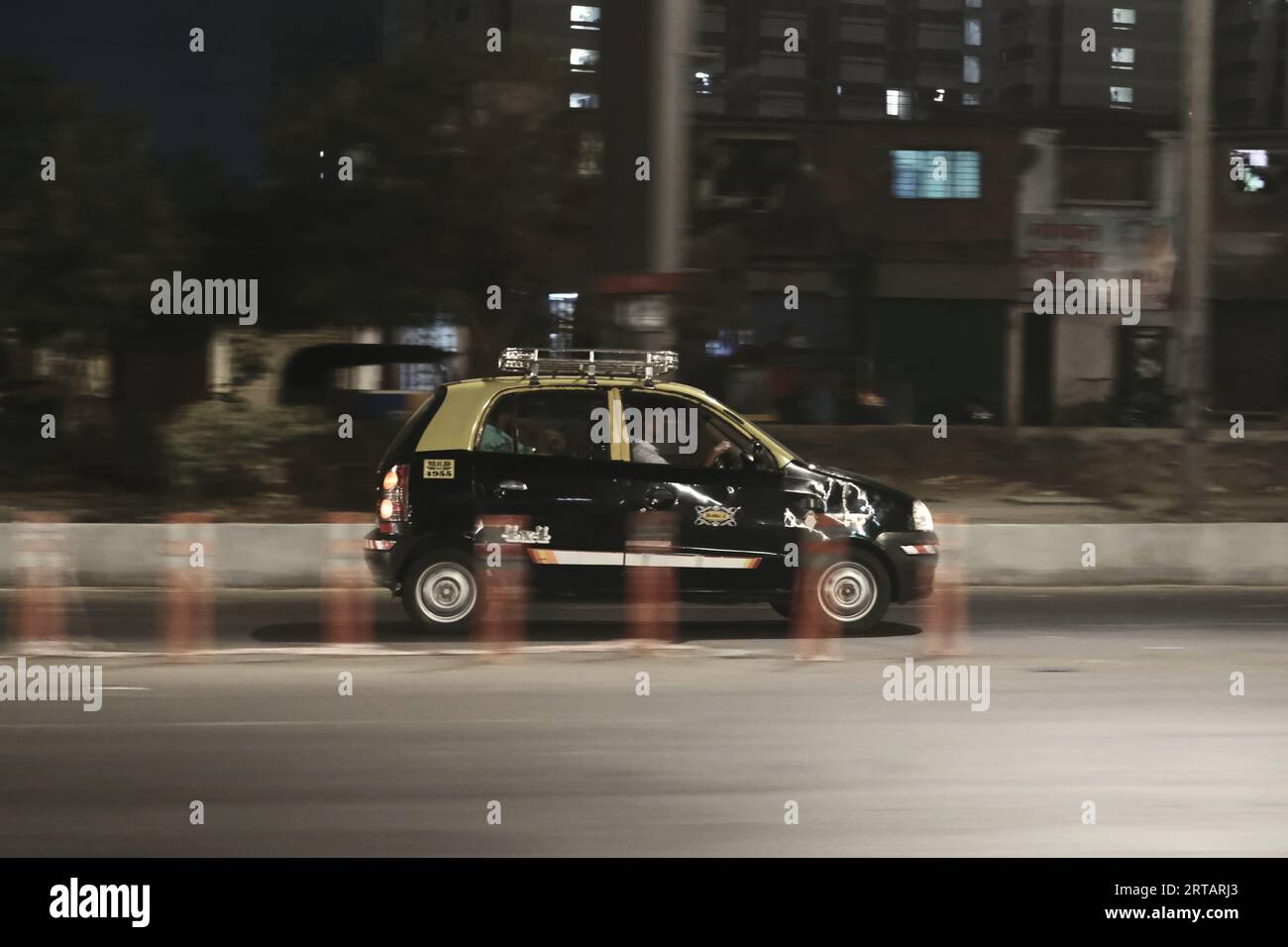A black and yellow cab driving through city at night Stock Photo - Alamy