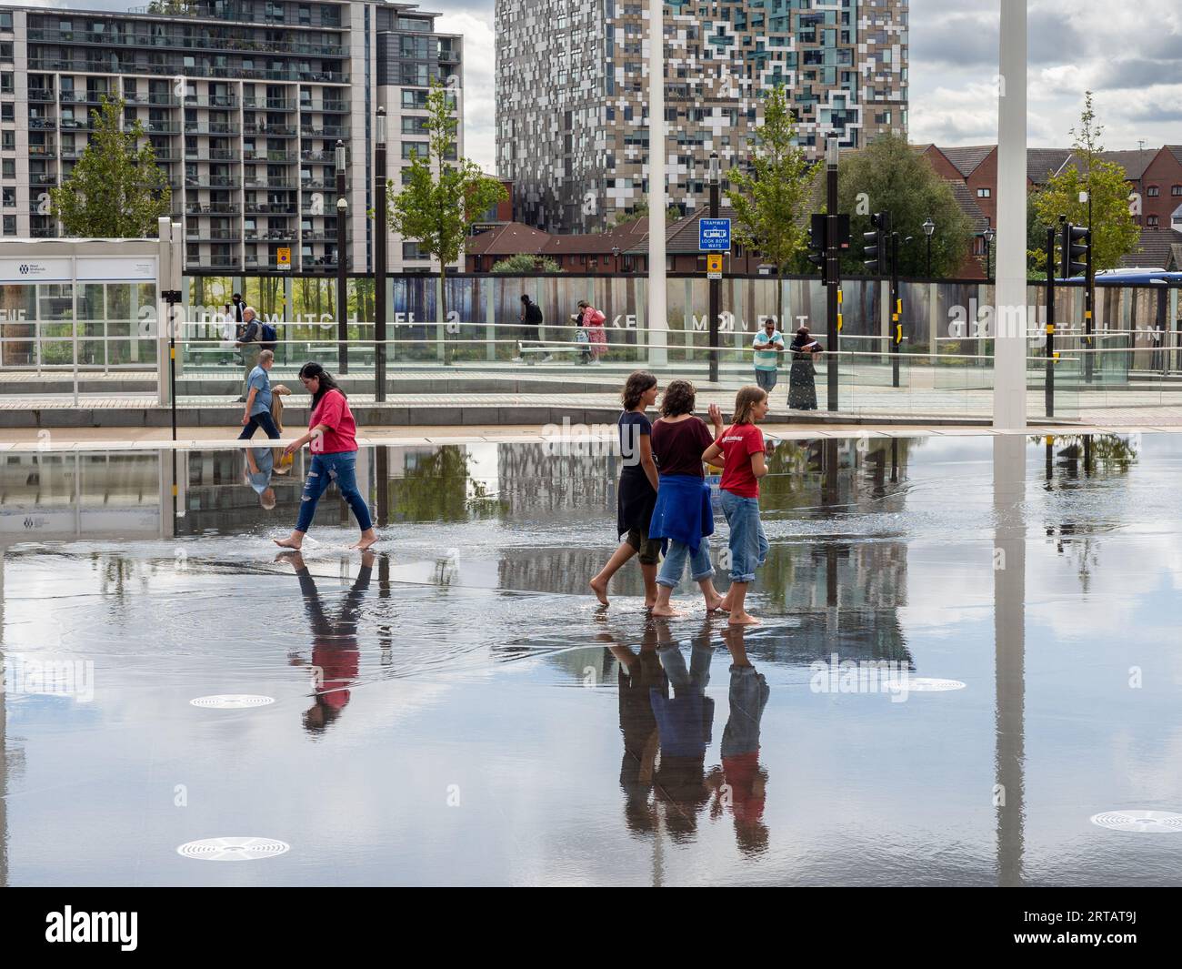 Visitors to Birmingham UK cool down in a shallow pool in Centenary ...