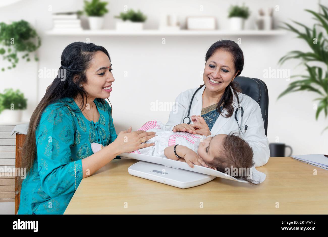 Young indian female pediatrician and mother measuring the weight of a ...