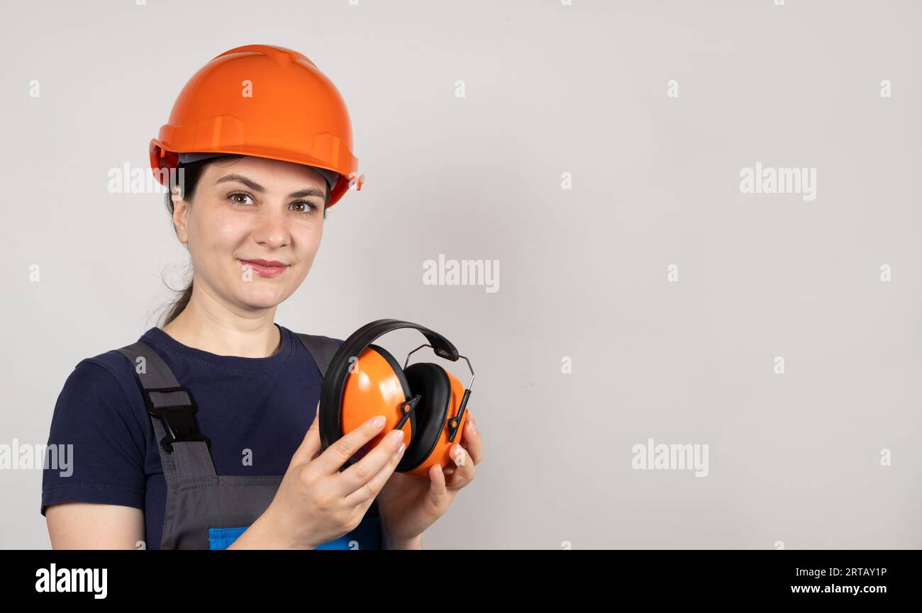 Female construction worker in protective helmet holding earmuffs on white background Stock Photo ...