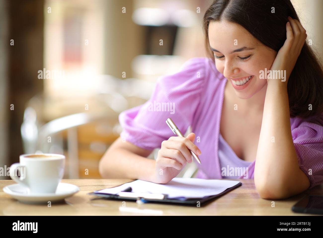 Happy woman reading and filling form in a restaurant terrace Stock ...