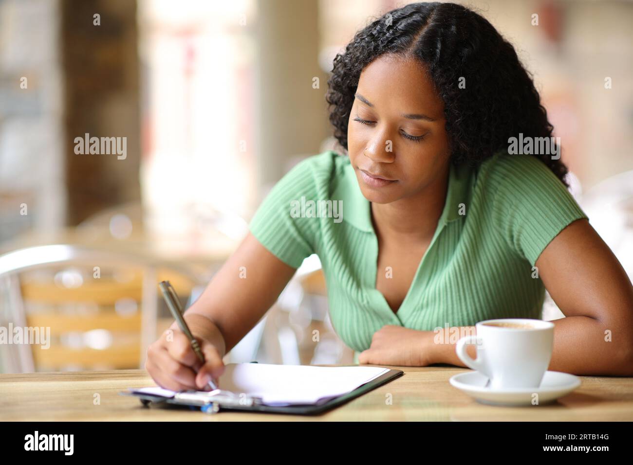 Black woman filling form or survey sitting in a bar terrace Stock Photo ...