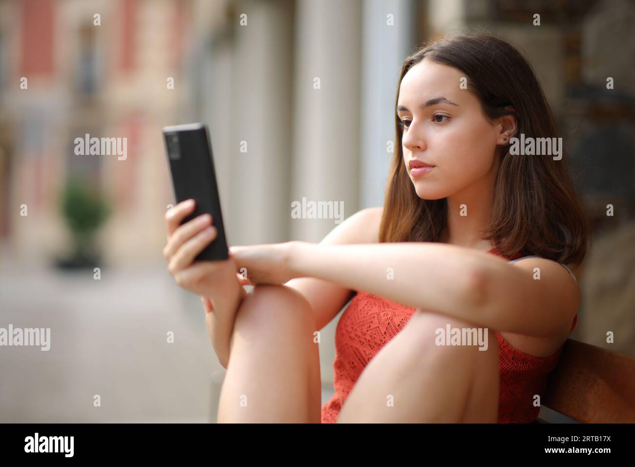 Serious woman checking phone content in the street Stock Photo - Alamy