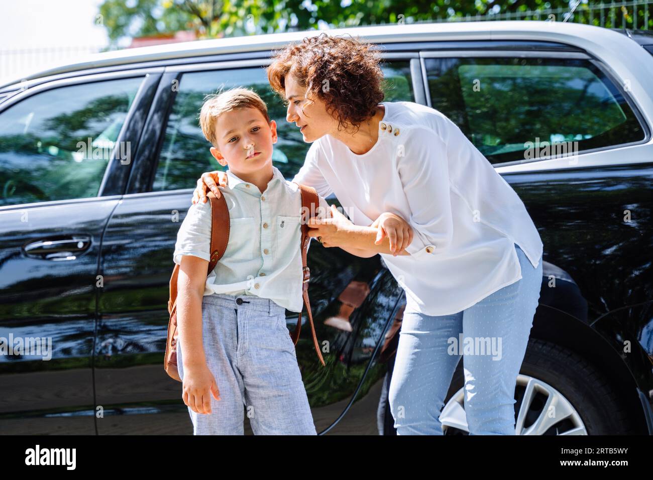 Back to school. A frustrated cute schoolboy with a backpack looks sadly ...